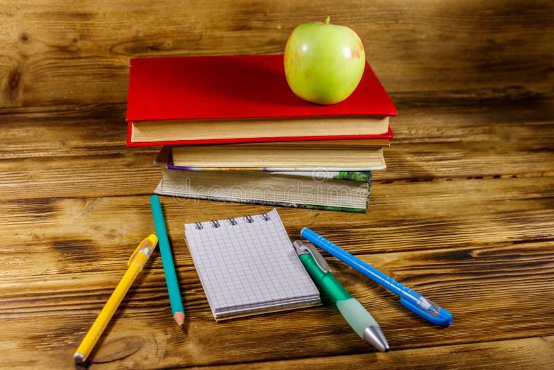 Stack of Books, Notepad, Pens, Pencils and Apple on Wooden Desk. Back ...