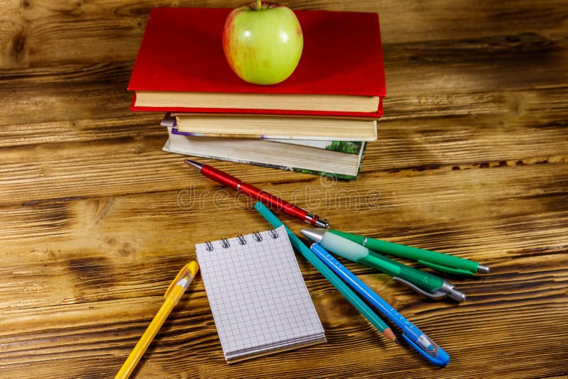 Stack of Books, Notepad, Pens, Pencils and Apple on Wooden Desk. Back ...
