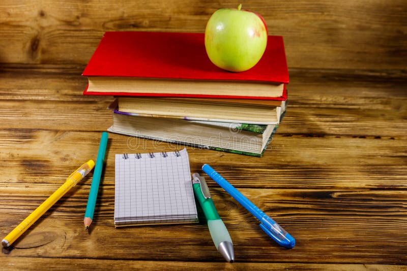 Stack of Books, Notepad, Pens, Pencils and Apple on Wooden Desk. Back ...