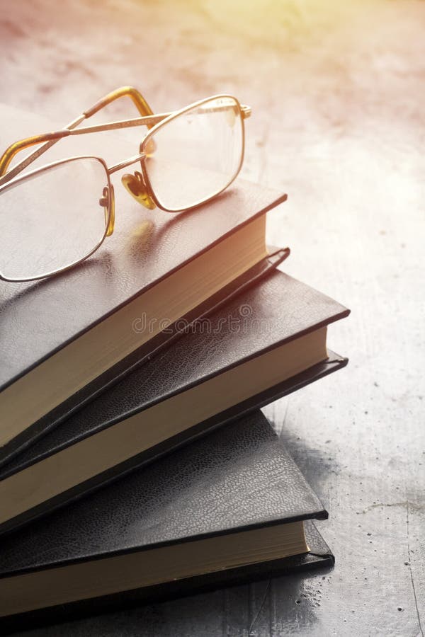 Stack of Books with a Pair of Eyeglasses on Top with Sun Effect. Stock ...