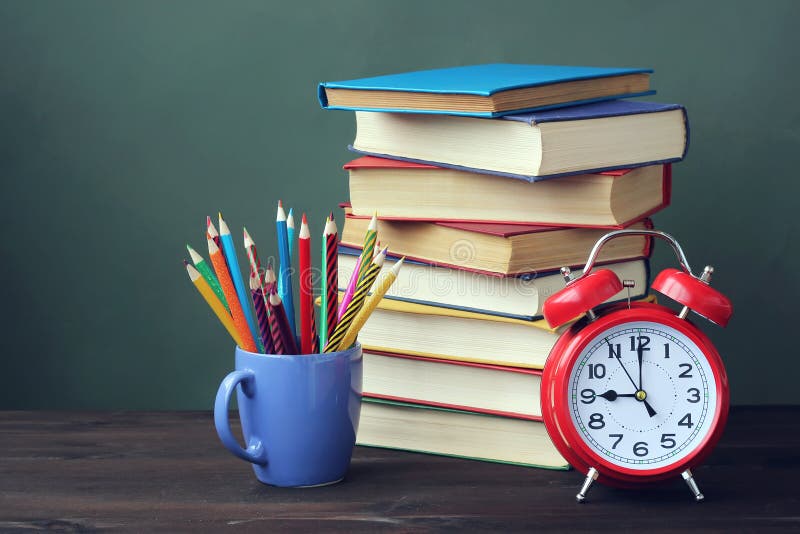 A Stack of Books, Pencils and Alarm Clock on the Table. Stock Photo ...