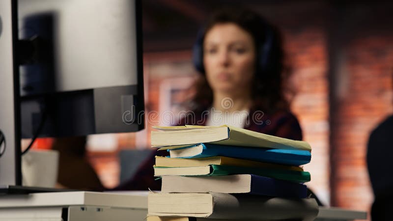 Stack of Books on Startup Office Desk in Front of Woman Working ...