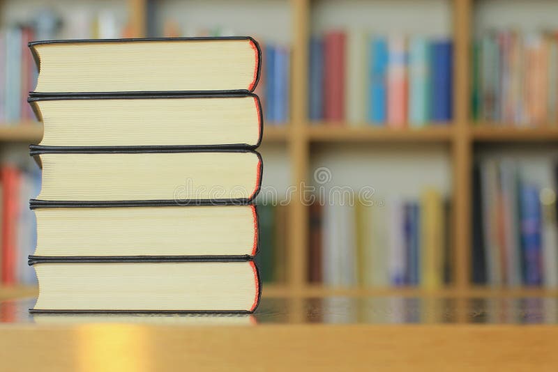 Stack of Books on the Table in Front of Bookshelf Stock Photo - Image ...