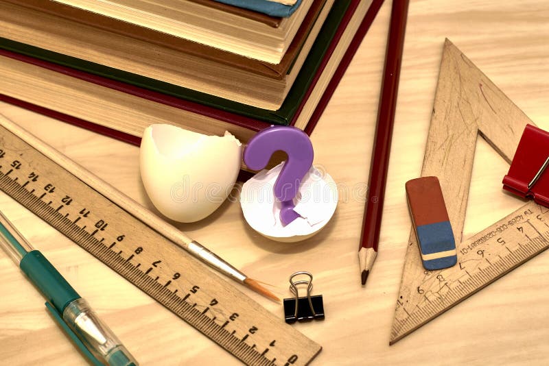 A Stack of Books Writing Materials Paper Clips and a Split Chicken Egg ...