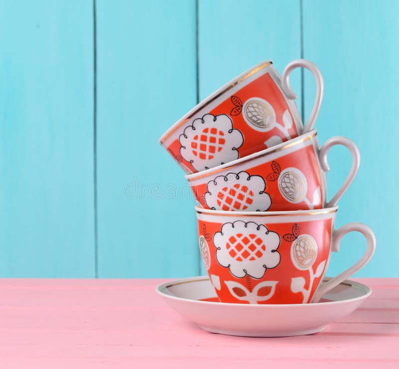 A Stack of Ceramic Retro Cups with Red Patterns on a Pink Wooden Table ...