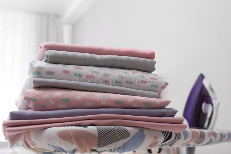 Stack of Clean Bed Linens on Ironing Board in Room Stock Photo - Image ...