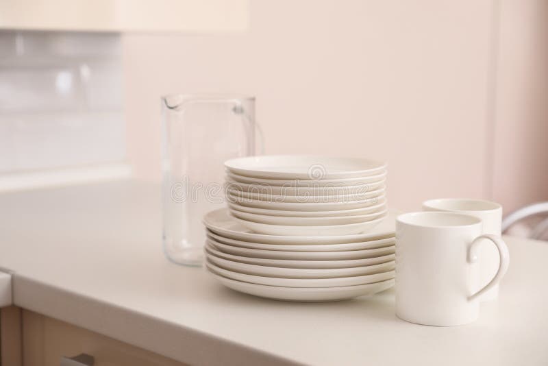 Stack of Clean Dishes, Cups and Glass Jug on Table Stock Photo - Image ...