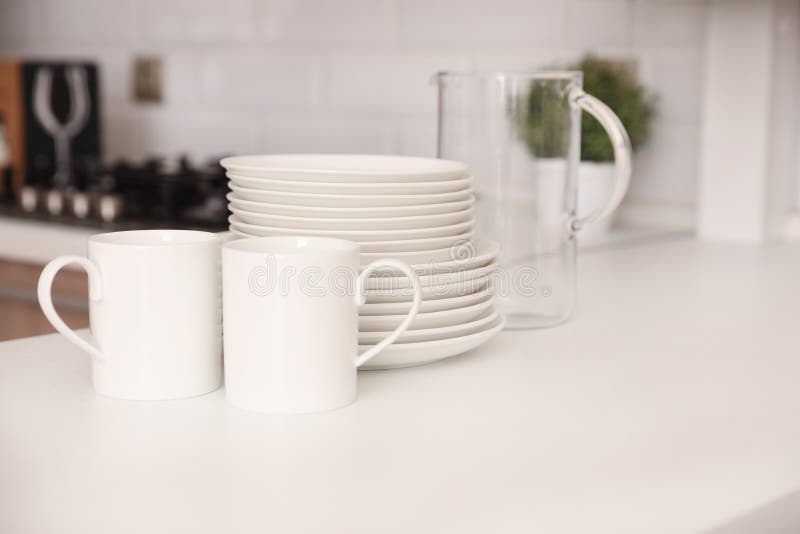 Stack of Clean Dishes, Cups and Glass Jug on Table Stock Image - Image ...