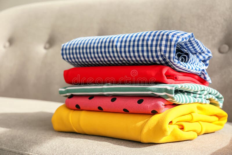 Stack of clothes on sofa stock image. Image of garment - 115682505