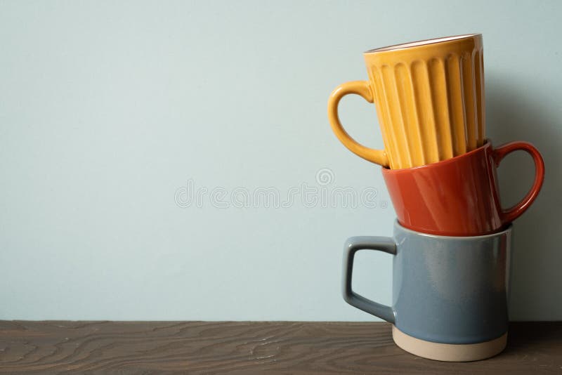 Stack of Colorful Ceramic Mug Cups on Wooden Table. Blue Wall ...