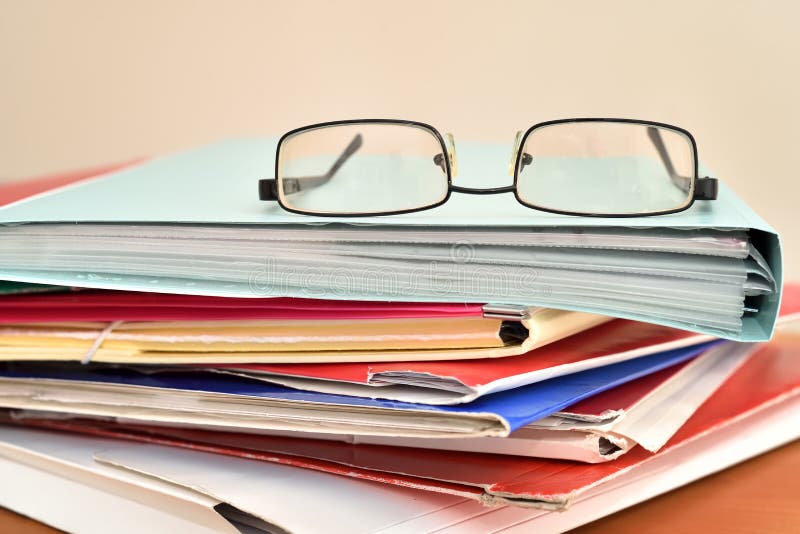 Stack of Document File Folders with Glasses on the Brown Wooden Office ... Stack of Document File Folders with Glasses on the Brown Wooden Office ...