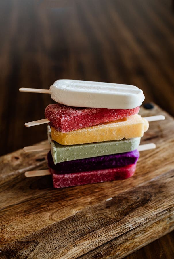 Stack of Colorful Popsicles on a Wooden Board with a Blurred Background ...