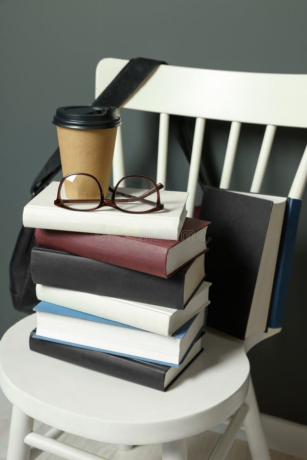 Stack of Different Books, Paper Cup and Glasses on White Chair Stock ...