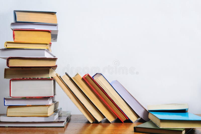 Stack of Different Books on a Table Against a White Wall Background ...