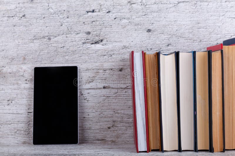 A Stack of Different Books and a Tablet. on a Wooden Background. the ...