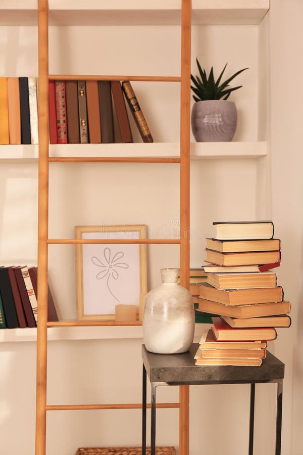 Stack of Different Books and Vase on Table Near Bookshelves in Home ...
