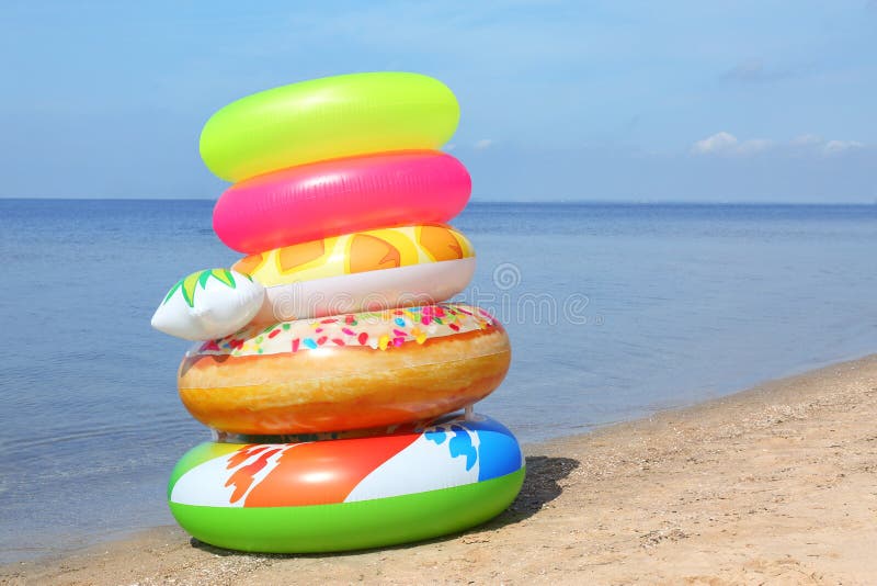 Stack of Different Bright Inflatable Rings on Sandy Beach Near Sea ...