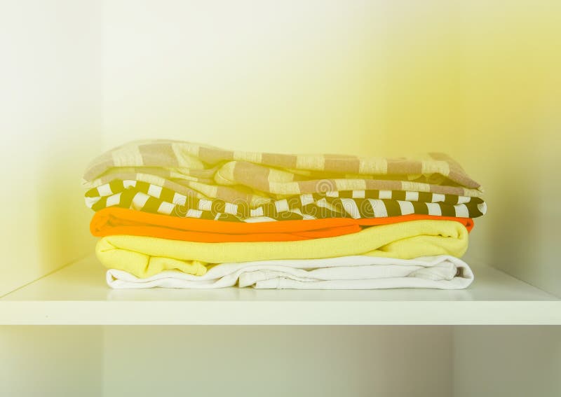 Stack of Different Clothes on White Wooden Wardrobe Shelf. Stock Image ...