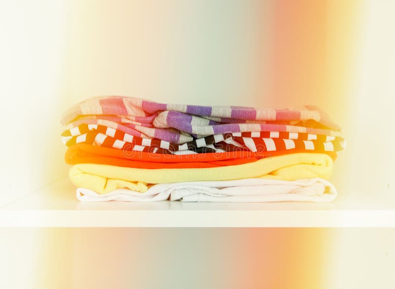 Stack of Different Clothes on White Wooden Wardrobe Shelf. Stock Photo ...
