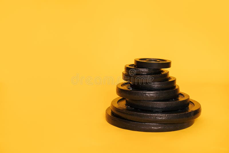 Stack of Discs of Different Weights on Yellow Background Stock Photo ...
