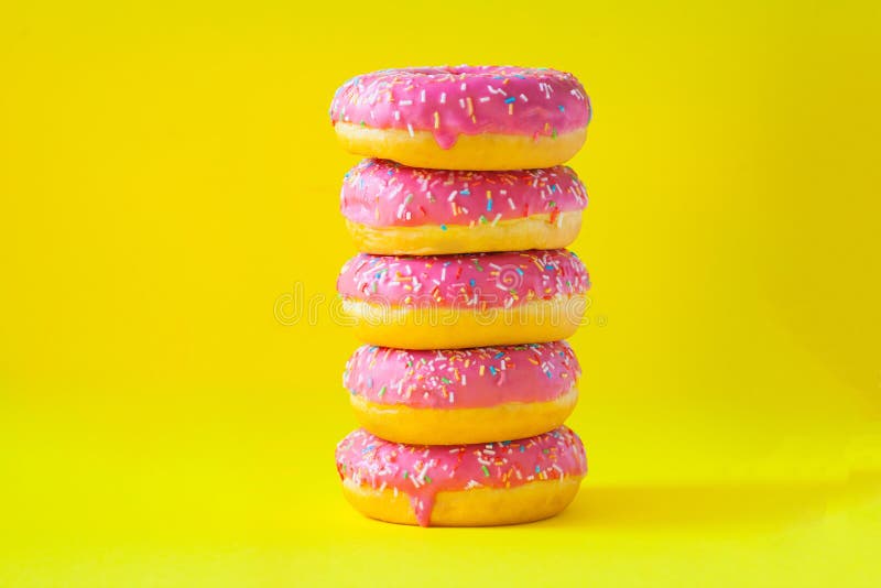 A Stack of Donuts with Pink Icing on a Yellow Background Side View ...