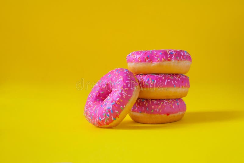 A Stack of Donuts with Pink Icing on a Yellow Background Side View ...