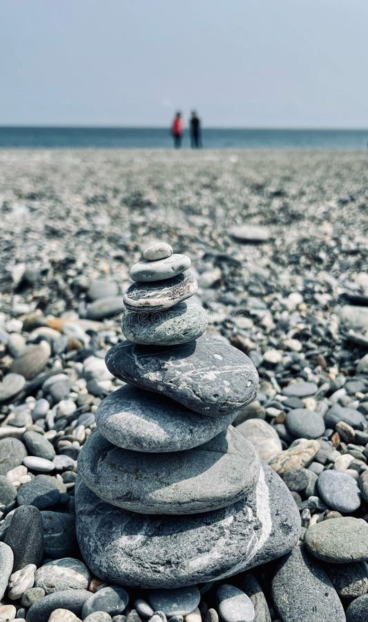 Stack of Flat Rocks on a Rocky Beach with People Standing on the ...