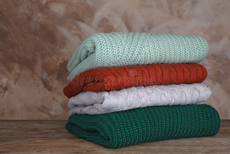 Stack of Folded Knitted Sweaters on Table Against Brown Background ...