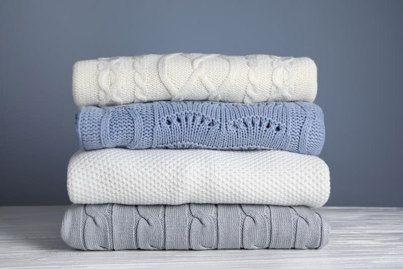 Stack of Folded Knitted Sweaters on Wooden Table Against Grey ...