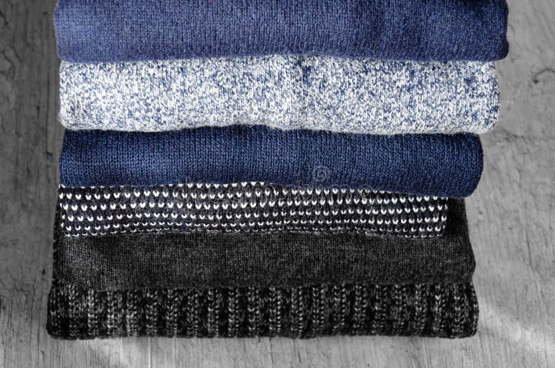 Stack of Folded Warm Knitted Men`s Sweaters on Gray Background. Closeup ...