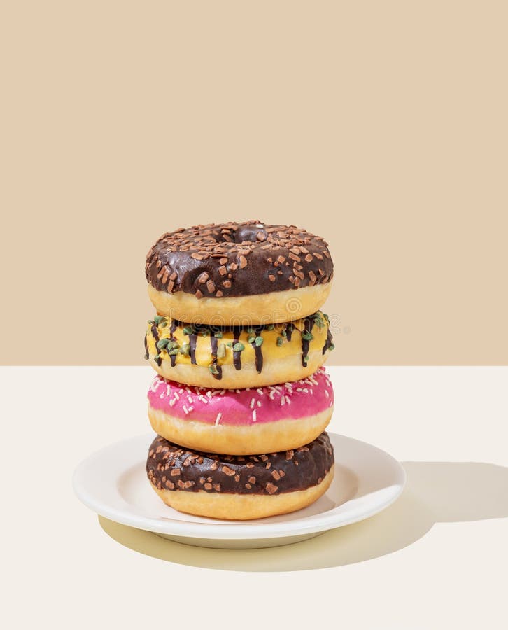 Stack of Glazed Donuts with Different Toppings on White Plate on Beige ...