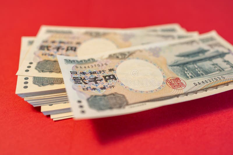 Stack of Japanese Yen Bills Displayed on a Red Surface, with a Focus on ...
