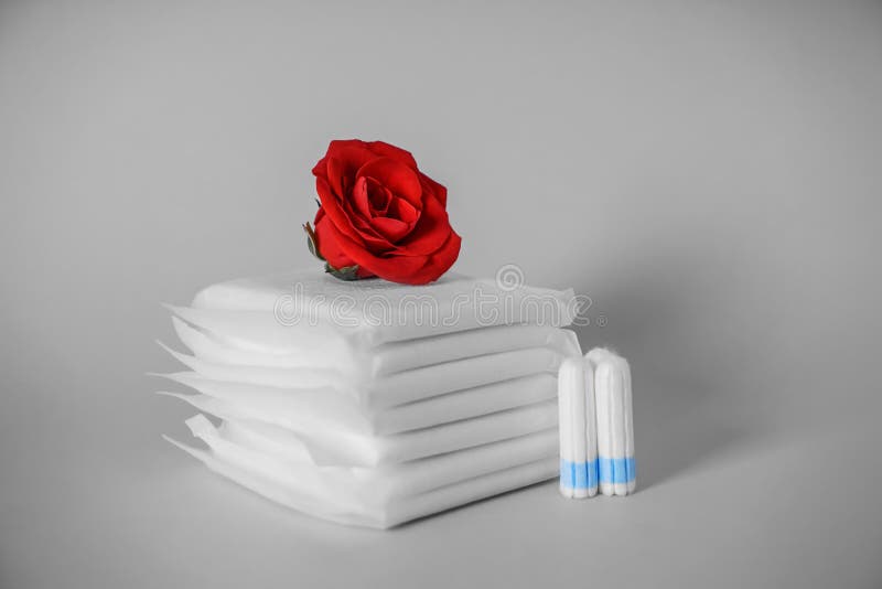 Stack of Menstrual Pads with Red Rose and Tampons on Grey Background ...