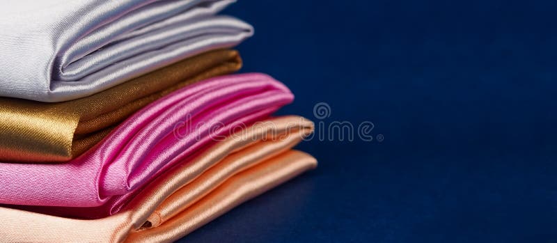 A Stack of Multi-colored Satin Fabric on a Blue Background, Space for ...