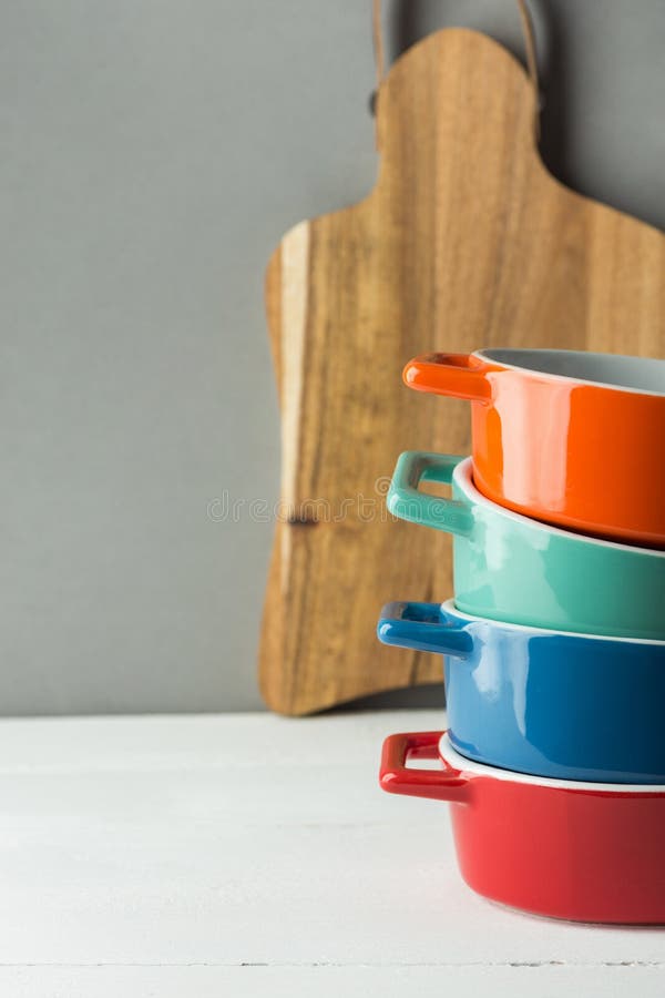 Stack of Multicolored Ceramic Cocottes Cutting Board on White Wood ...