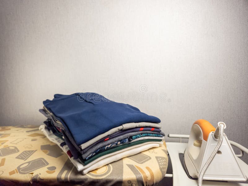 Stack of Neatly Folded Clothes and an Iron on an Ironing Board Stock ...