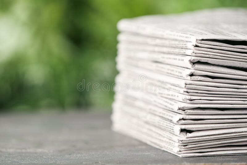 Stack of Newspapers on Grey Table Against Blurred Green Background ...