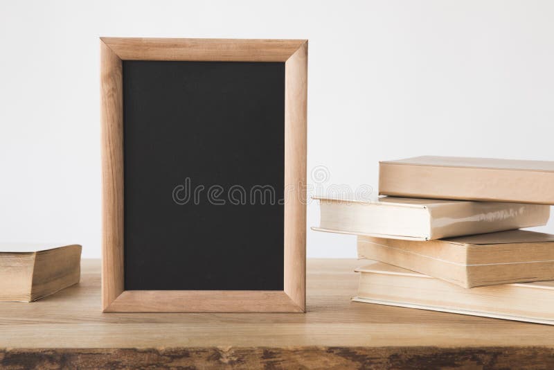 Stack of Old Books and Blackboard in Frame on Wooden Table on White ...