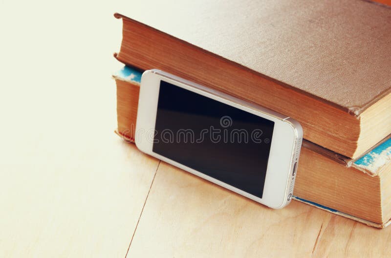 Stack of Old Books and Smart Phone Over Wooden Table, Retro Filtered ...
