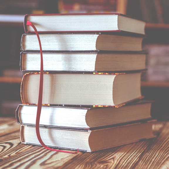 A Stack of Old Books on Table Against Background of Bookshelf in ...