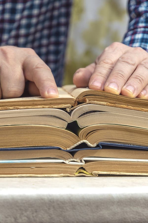 A Stack of Open Old Books and a Hand Searching for the Right Line on ...