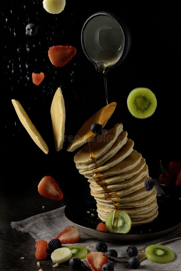 A Stack of Pancakes Toppling Over with Fruit and Syrup Falling All ...