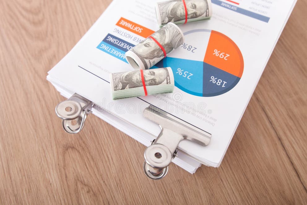 A Stack of Paper Business Documents and Several Rolls of Dollar Bills ...