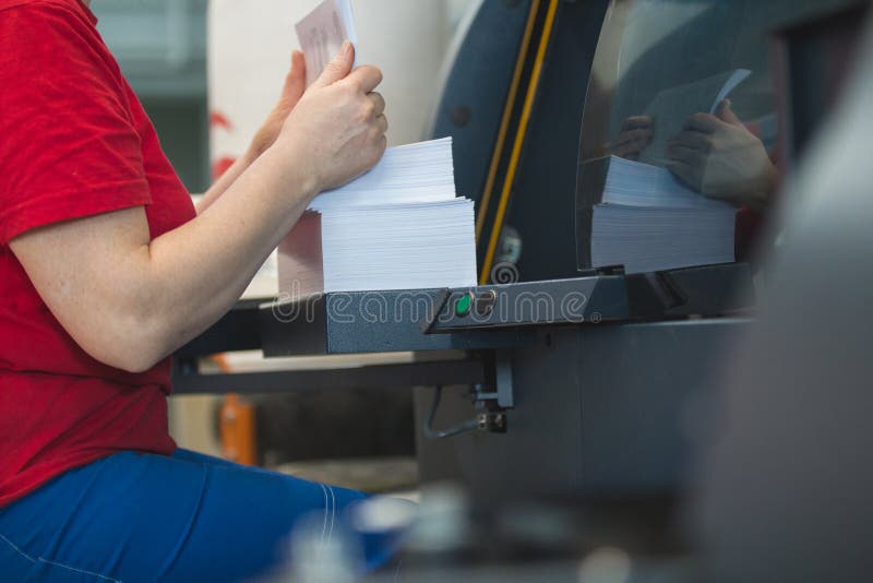 Stack of Paper in Hands of Female Worker in Front of Printing Press ...