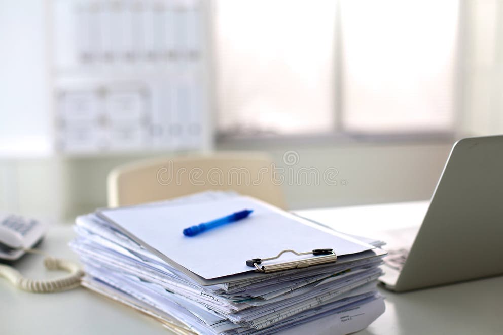 A Stack of Papers on the Desk with a Computer Stock Photo - Image of ...