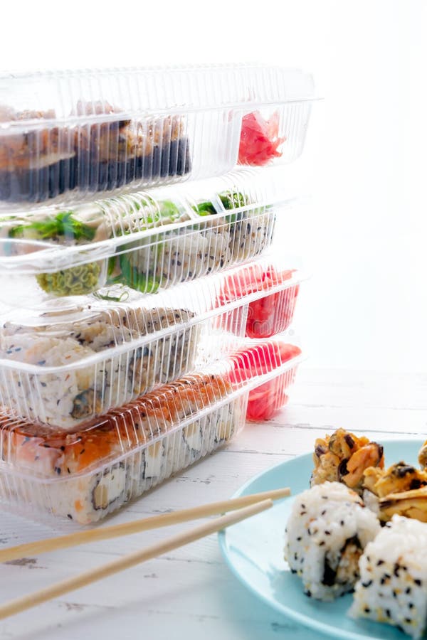 Stack of Plastic Boxes with Sushi Rolls, a Plate with Sushi on Table ...
