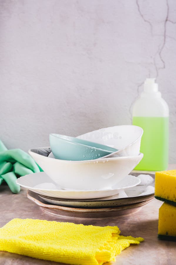 Stack of Plates in Foam, Cloth, Sponges, Gloves and Detergent on Table ...