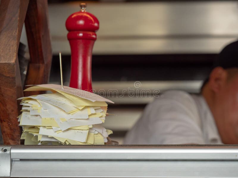 Stack of Receipts on Diner Serving Counter with Cook Working Behind ...