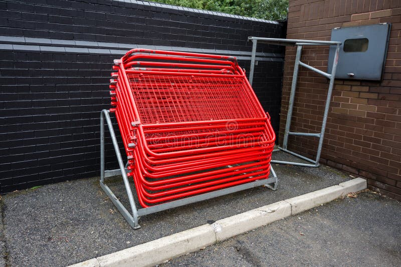 Stack of Red Metal Barriers Neatly Arranged on a Rack Against a Black ...