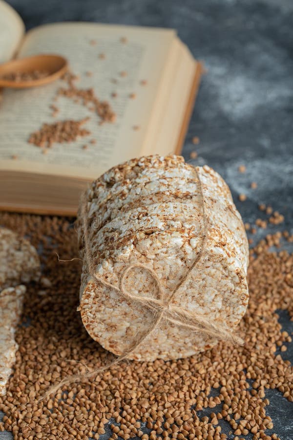 Stack of Rice Cakes, Book and Uncooked Buckwheat on Marble Surface ...
